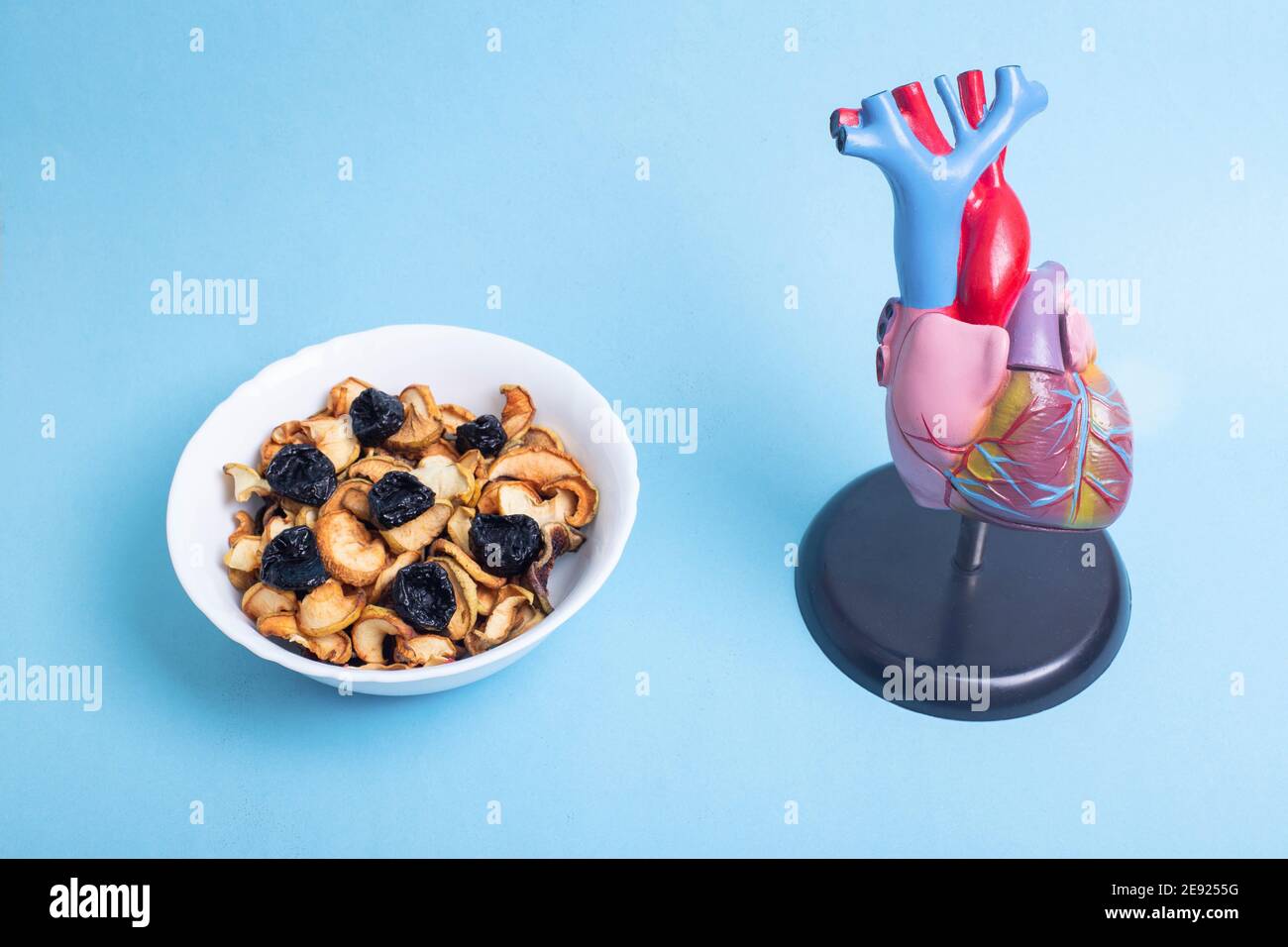 Human heart mockup and plate with dried fruits on a blue background ...