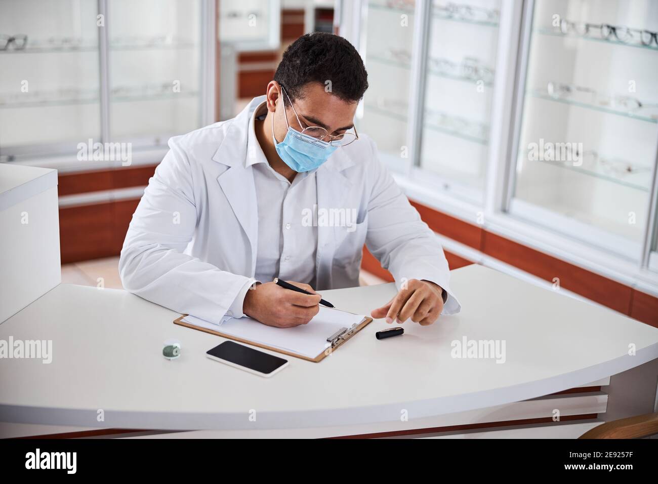 Concentrated eye doctor leaning over a sheet of paper Stock Photo - Alamy