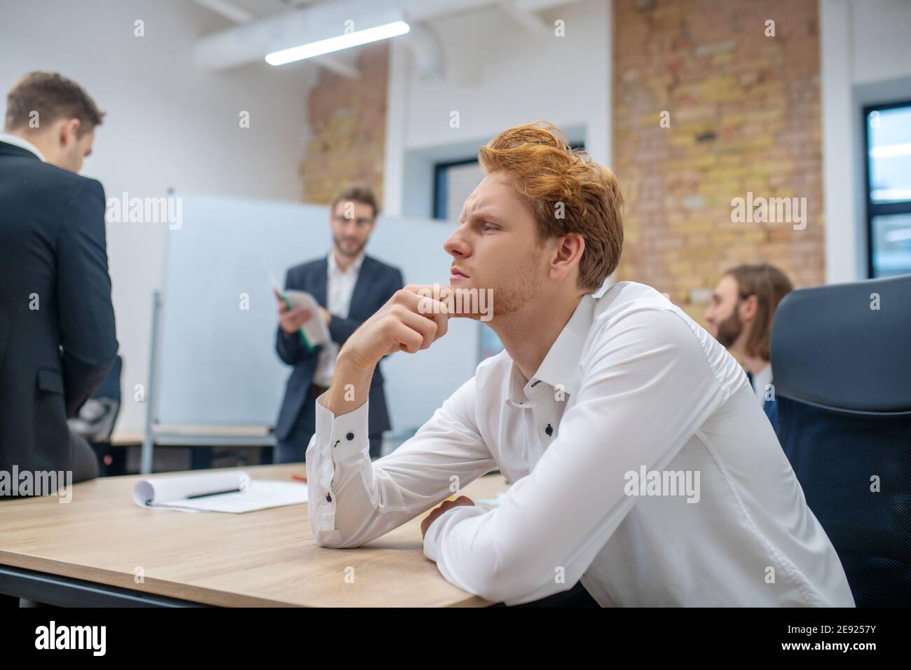 Thinking man in profile at table and colleagues Stock Photo - Alamy