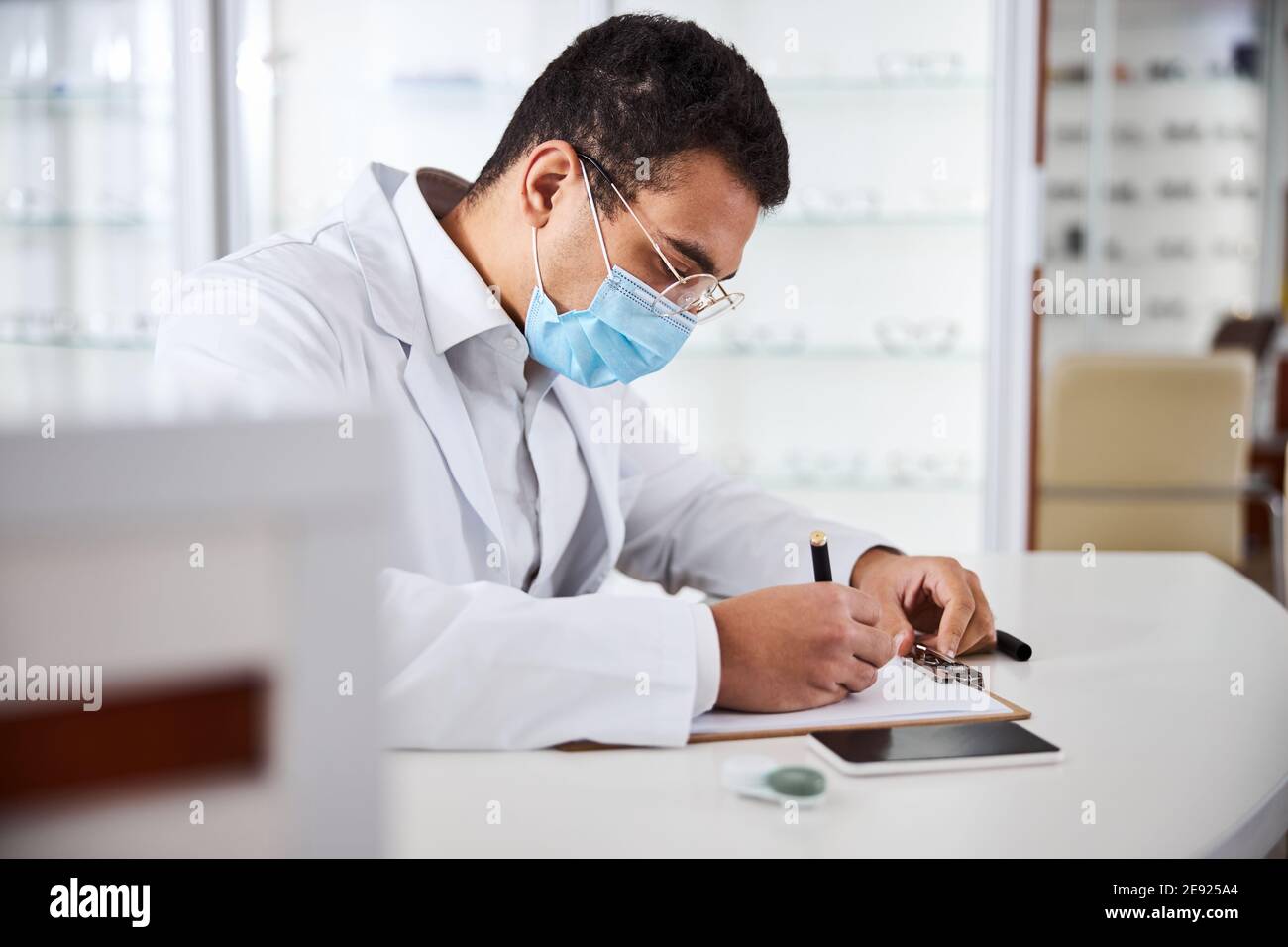 Serious concentrated optometrist working in his office Stock Photo - Alamy
