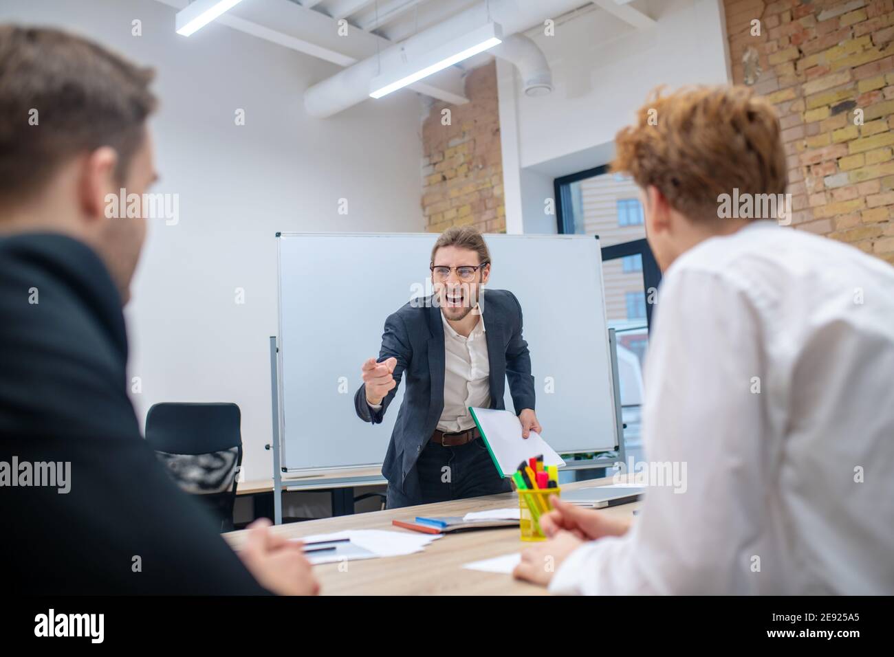 Angry man with glasses yelling at employees Stock Photo - Alamy