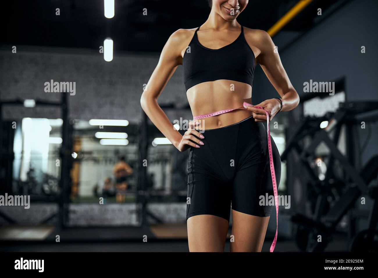 Focused photo on delighted female measuring her waist Stock Photo - Alamy