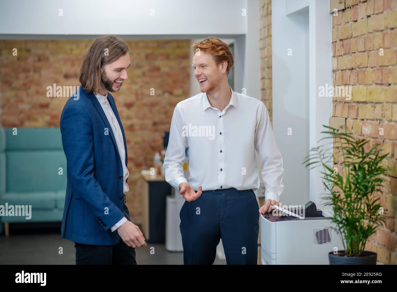 Joyful men communicating in office corridor Stock Photo - Alamy
