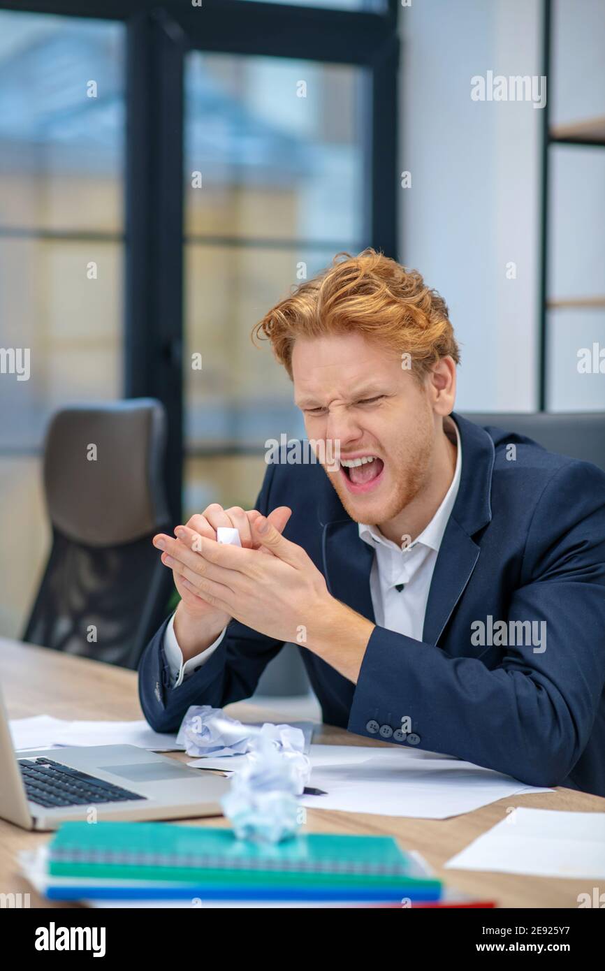 Nervous young man clumping paper in hands Stock Photo - Alamy