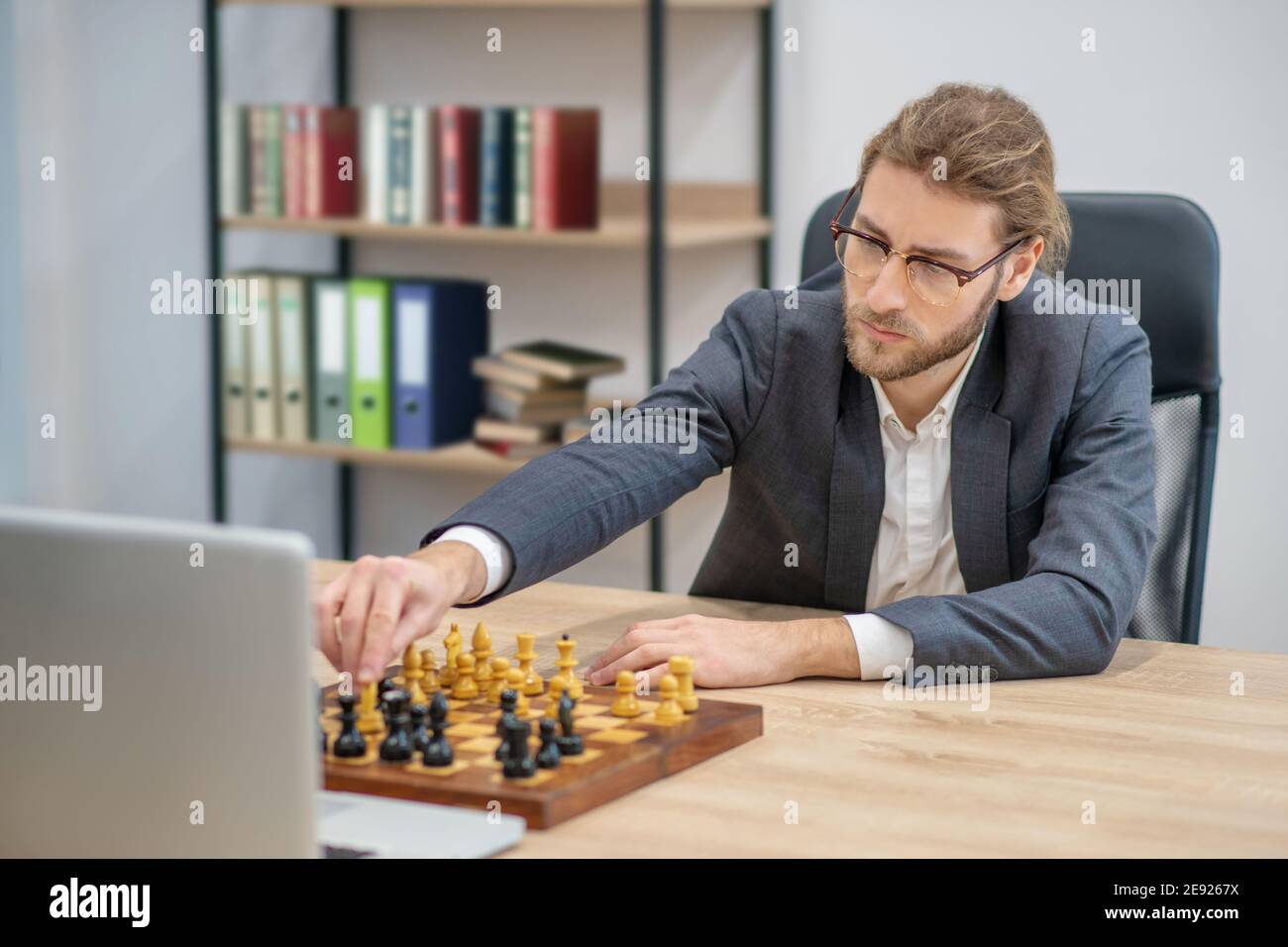 Serious man playing chess in front of laptop Stock Photo - Alamy