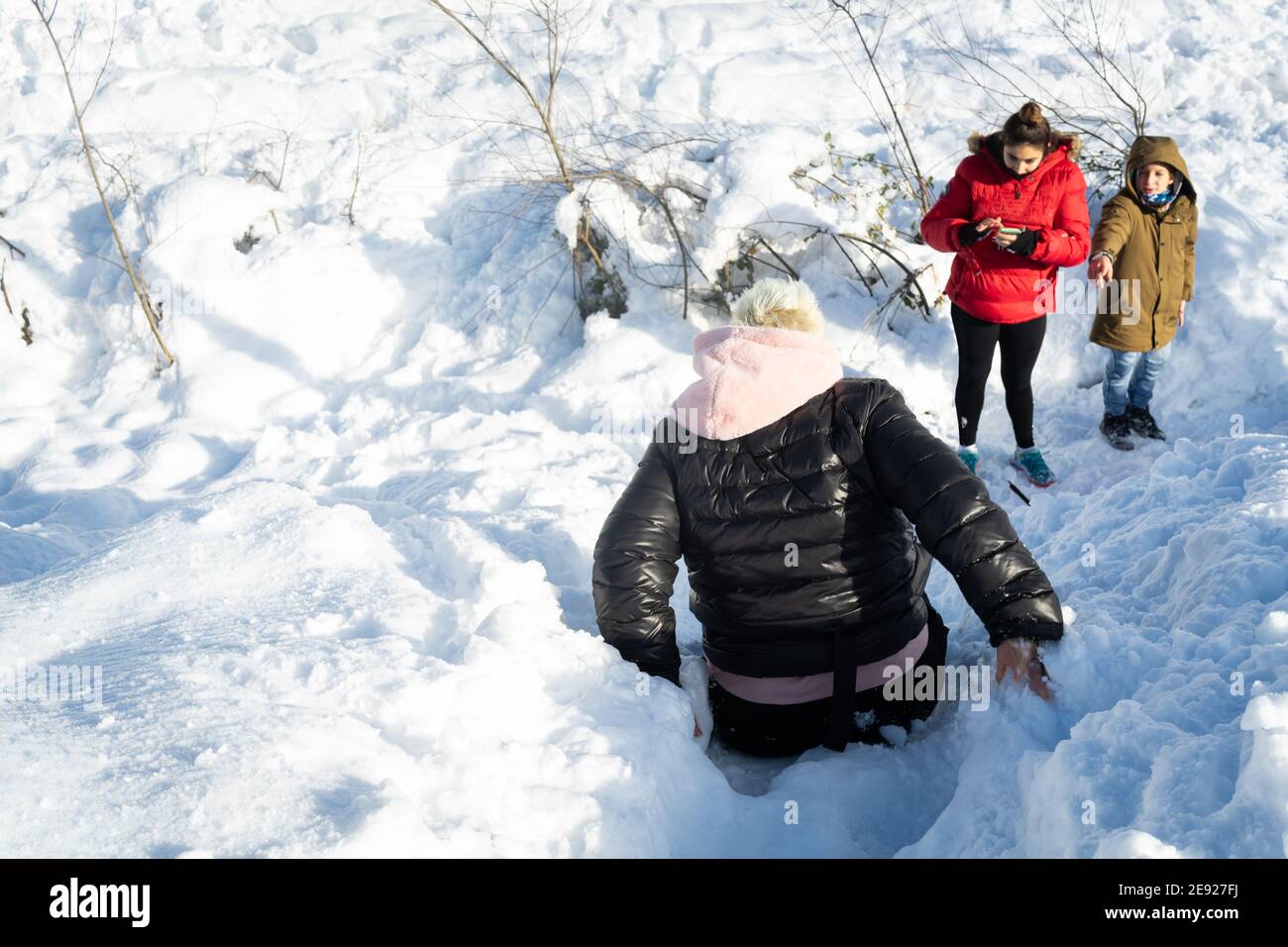 Back view of a woman in a coat sitting on snow enjoying time with her ...