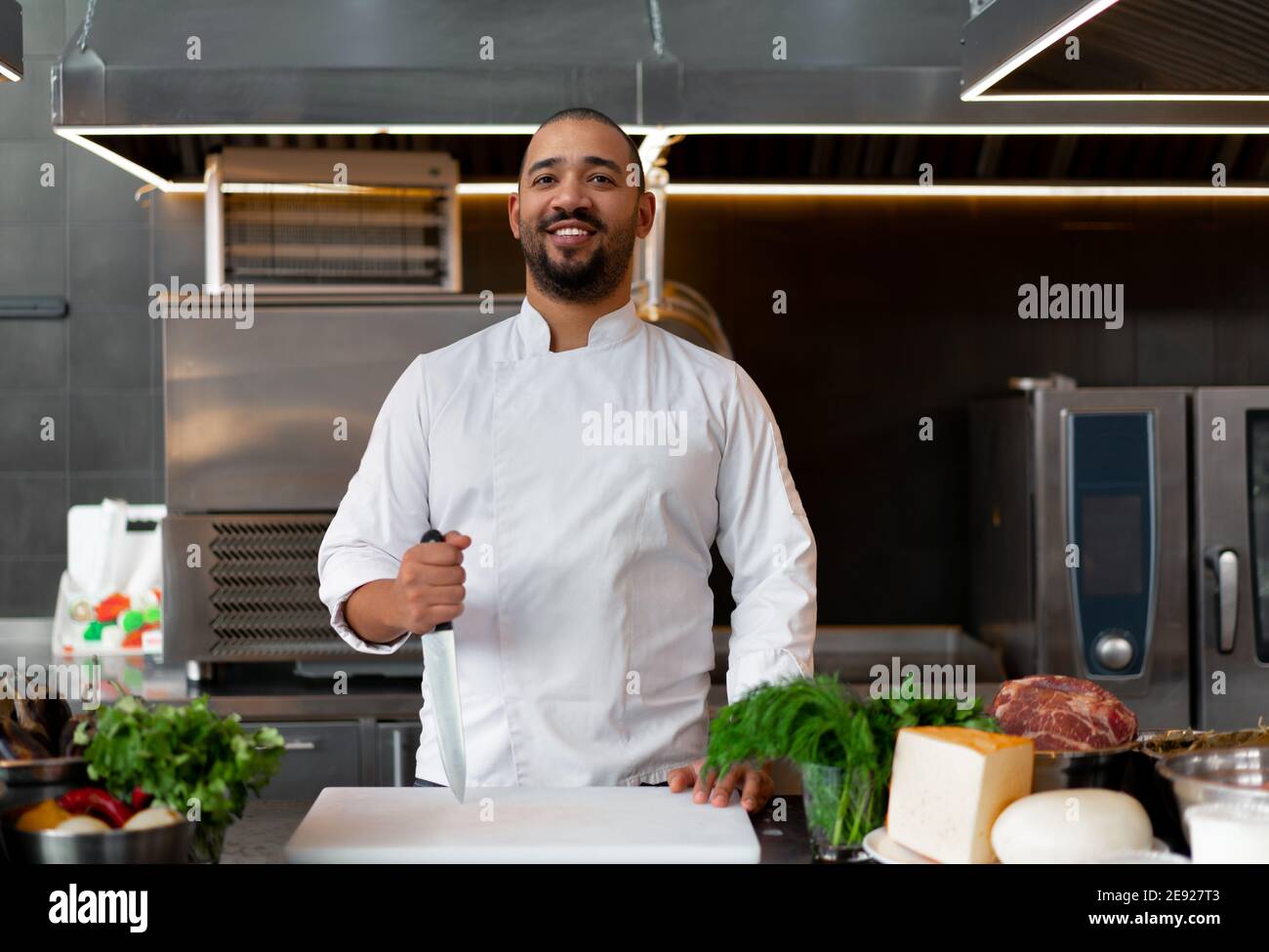 Handsome young African chef standing in professional kitchen in ...