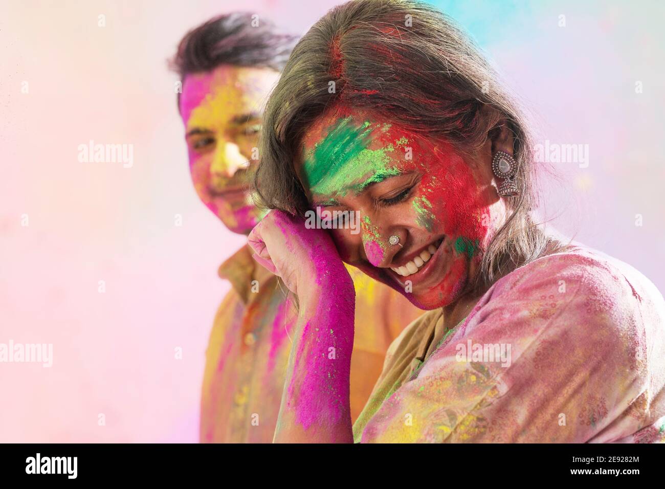 Woman smiling shyly with her husband looking at her in awe on Holi ...