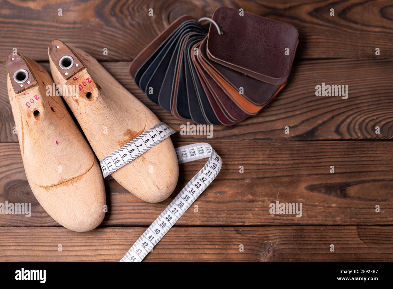 Leather samples for shoes and wooden shoe last on dark wooden table ...