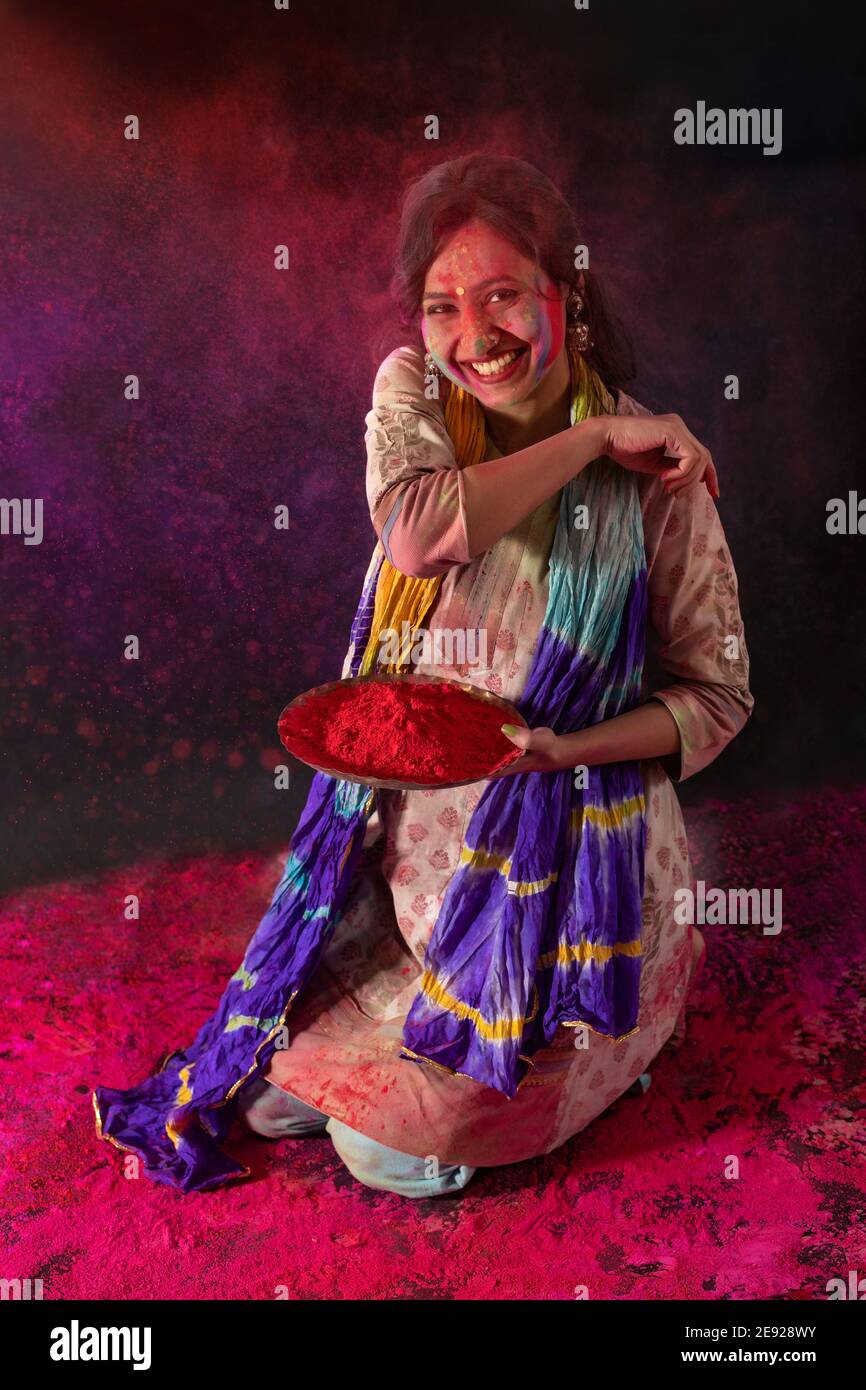 Woman with a plate in her hand throwing gulal on Holi Stock Photo - Alamy