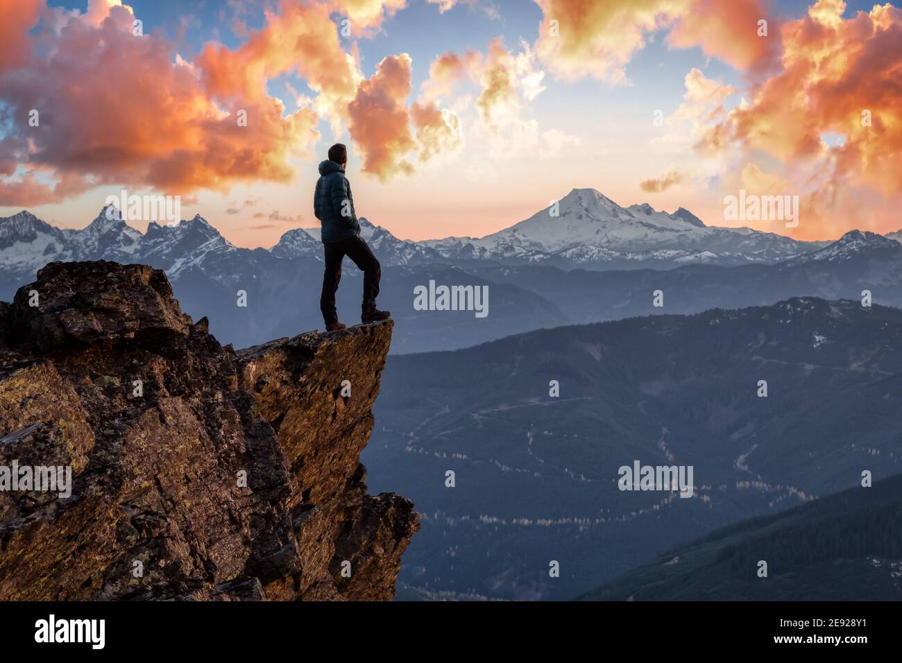 Adventurous man is standing on top of the mountain Stock Photo - Alamy