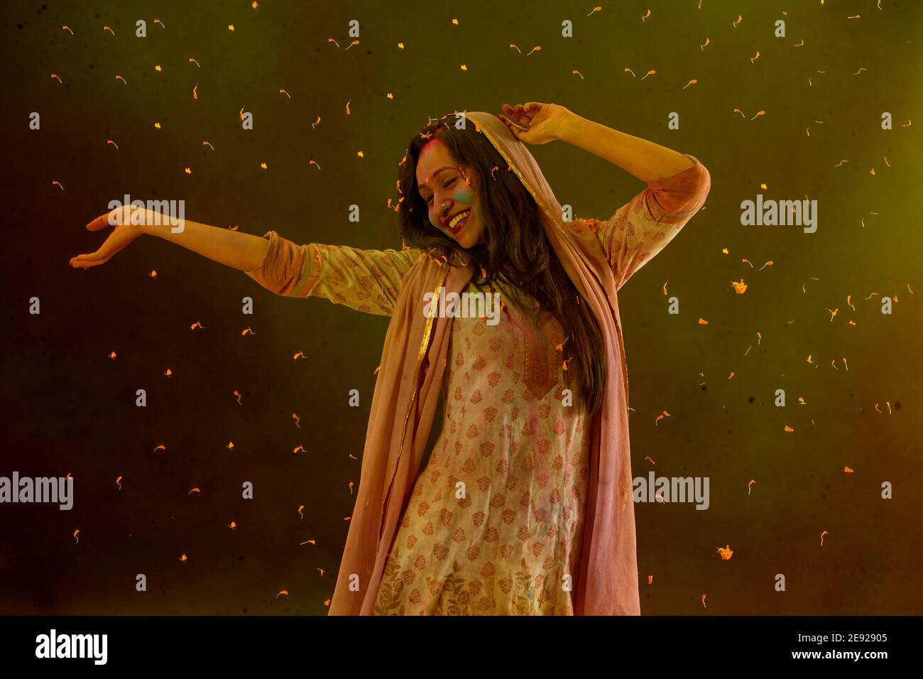 Woman dancing with flower petals around her on Holi Stock Photo - Alamy