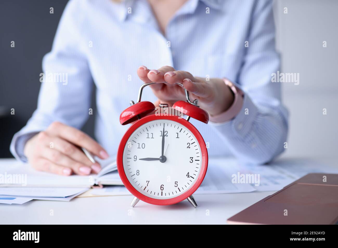 Female hand turning off red alarm clock at workplace closeup Stock ...