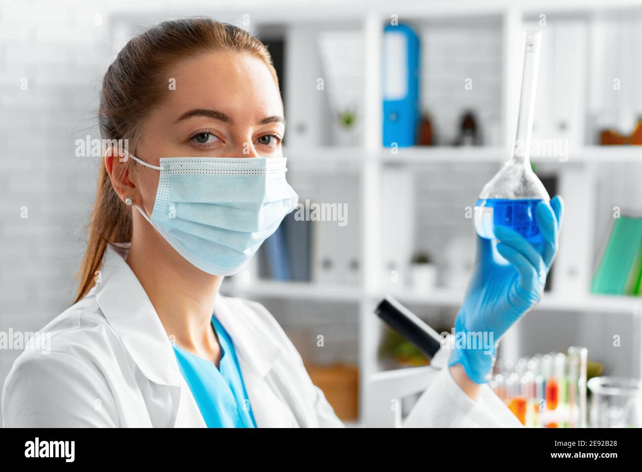 Woman scientist or laboratory worker holding glass flask with chemical ...