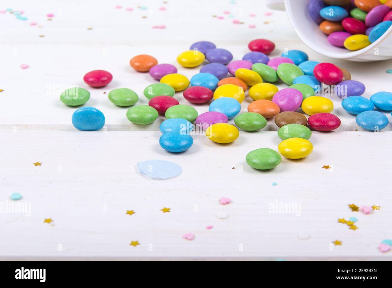 Colored candy bonbons scattered on white wooden board background Studio ...
