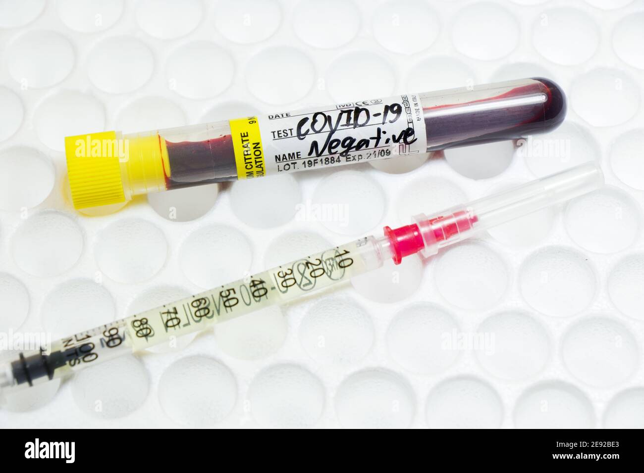 High angle shot of negative COVID-19 specimen on test tube and syringe ...