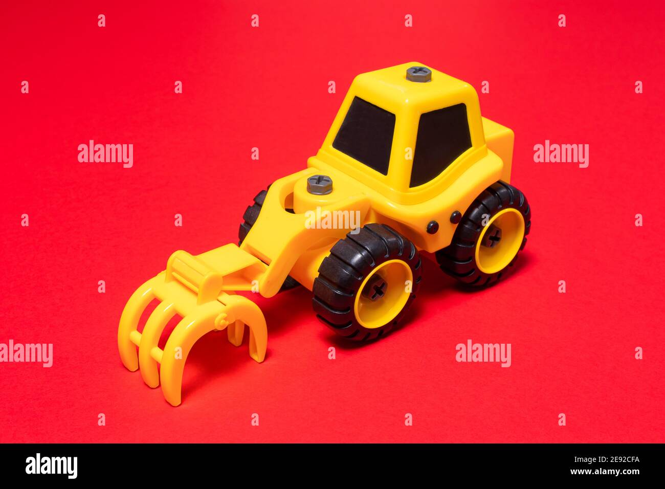 Yellow toy tractor with rake nozzle to load the forest on a red ...