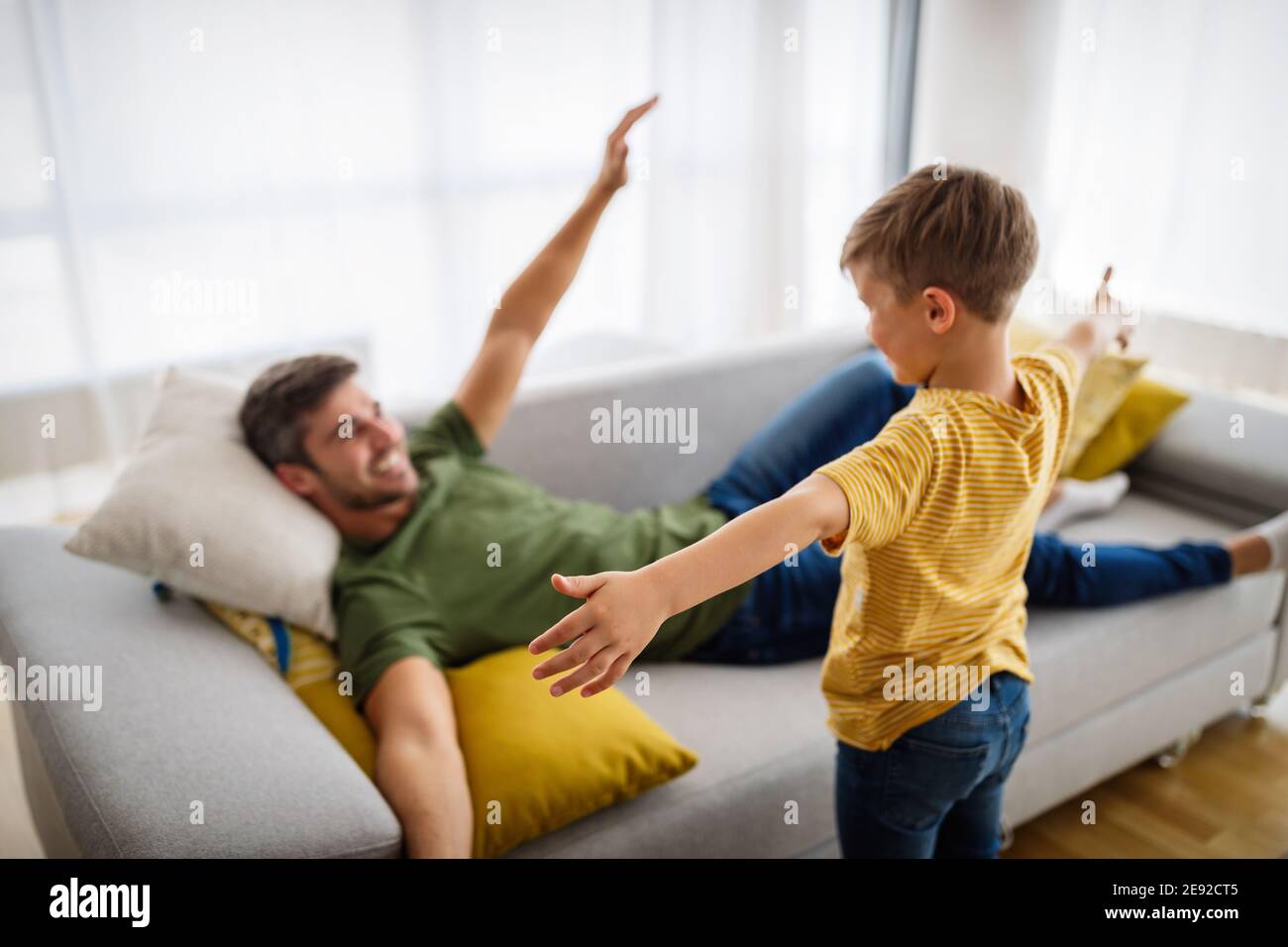 Happy father and son are smiling while spending time together at home ...