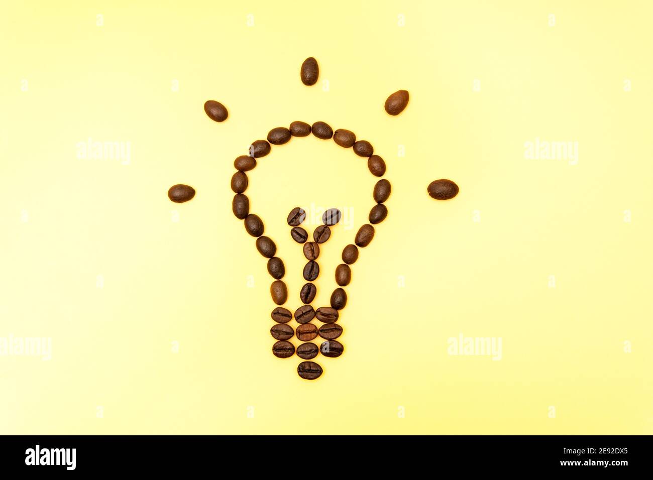 Glowing light bulb shape made of coffee beans on yellow background ...