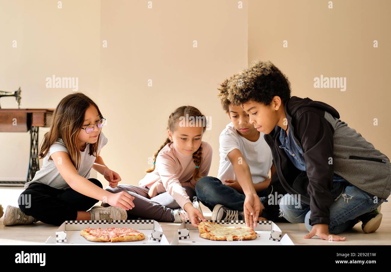 Group of pretty multi racial kids little boys girls sit indoor eating ...