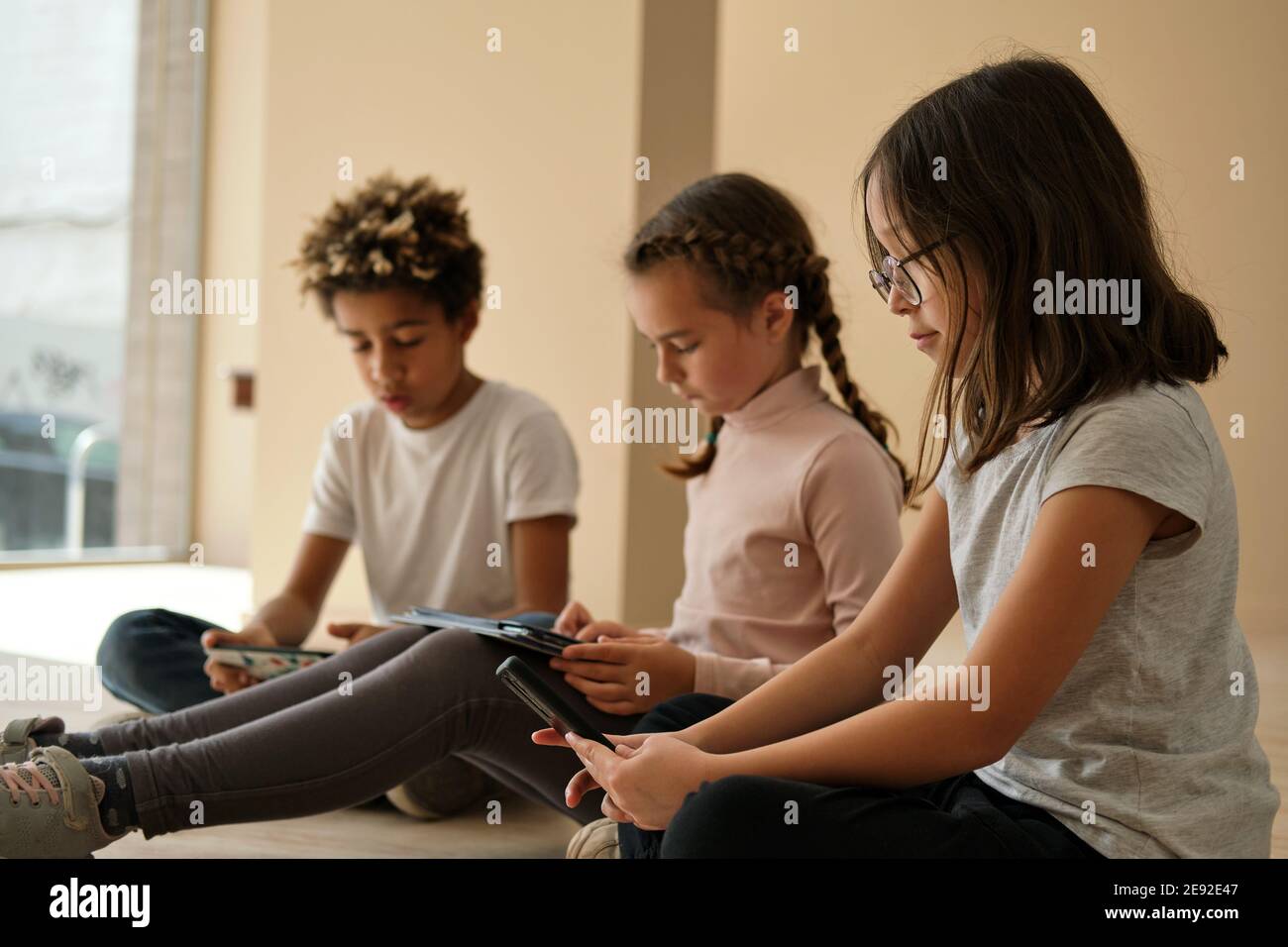 Three multi ethnic african, caucasian and korean little kids sit indoor ...