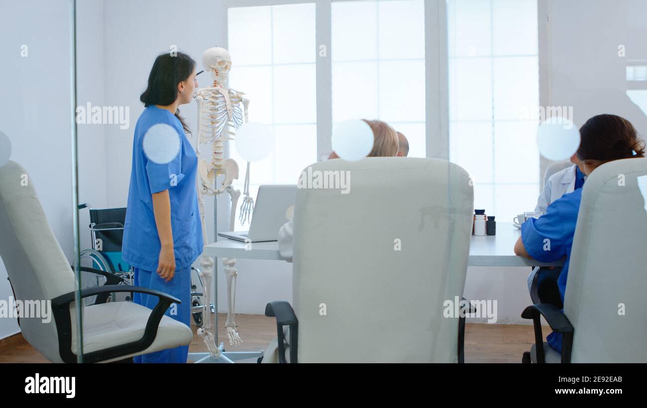 Medical nurse pointing on cervical spine of human skeleton anatomical ...