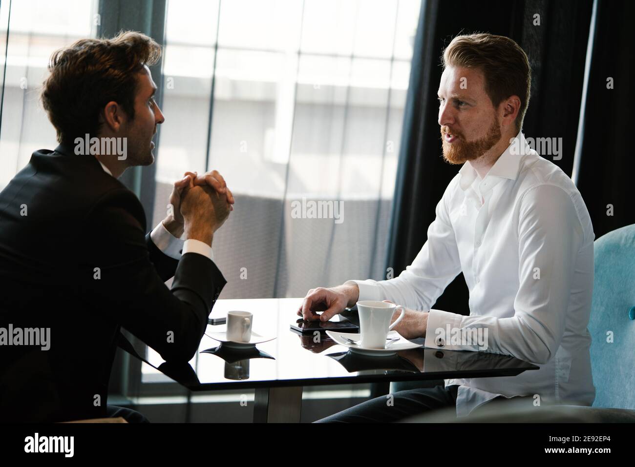 Colleagues and friends. Two cheerful businessmen drinking coffee and ...