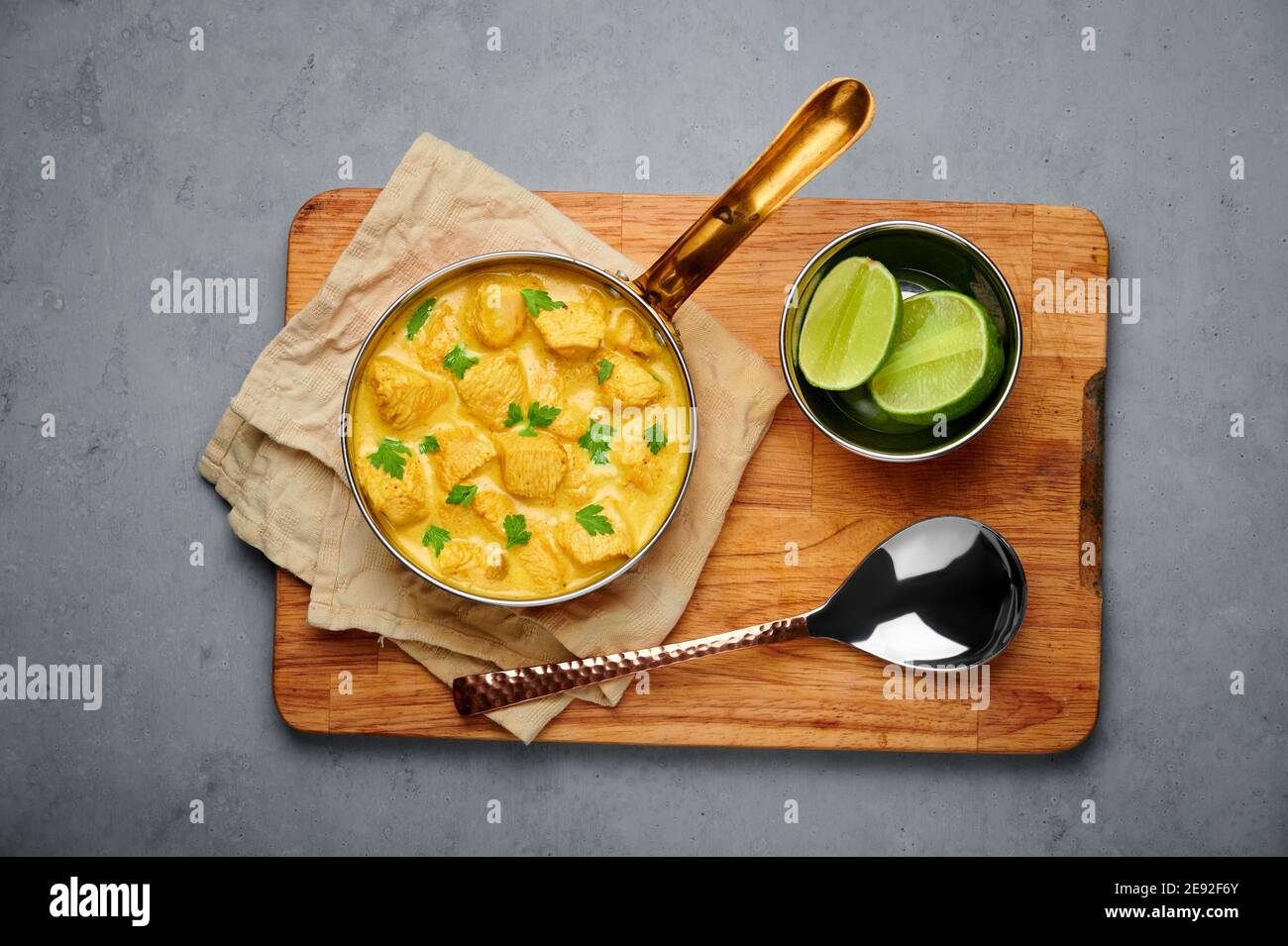 Chicken Korma in copper pan on gray concrete table top. Indian cuisine ...