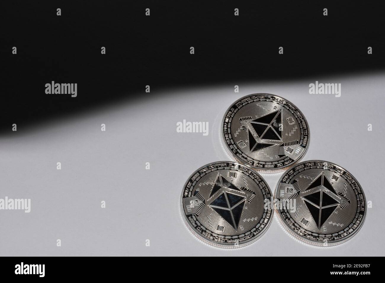 three silver ether coins from cryptocurrency on white and black ...