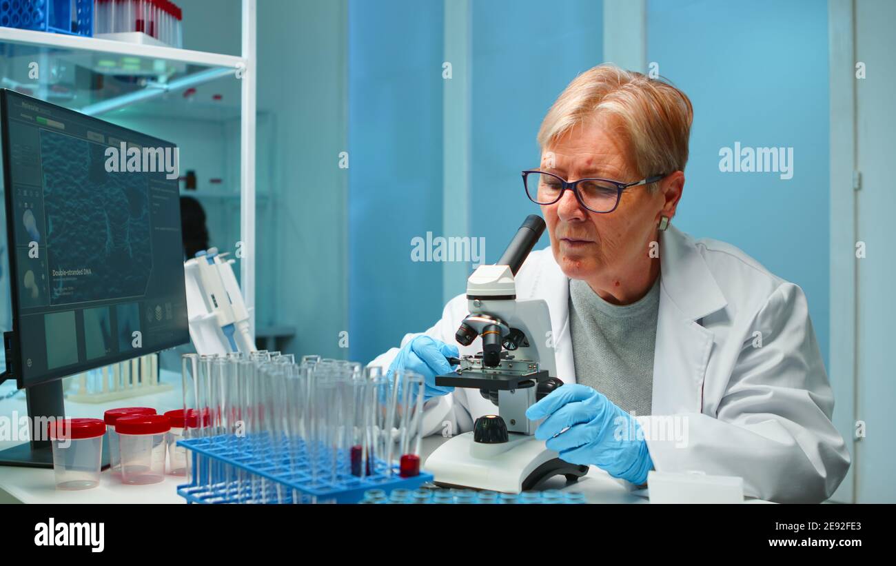 Woman research scientist looking at samples under microscope in modern ...