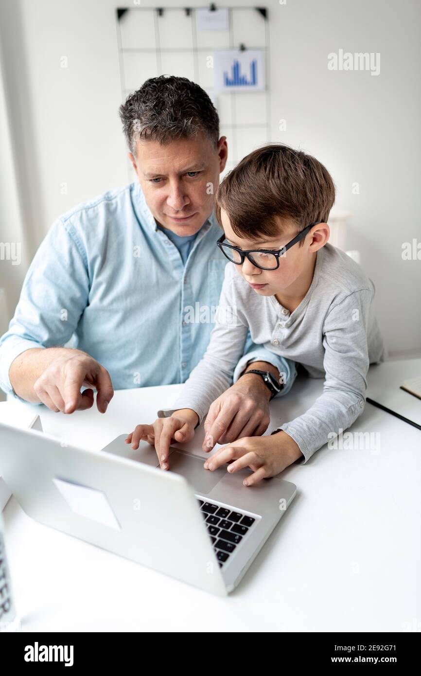 Father and son sitting in front of the laptop, working from home Stock ...