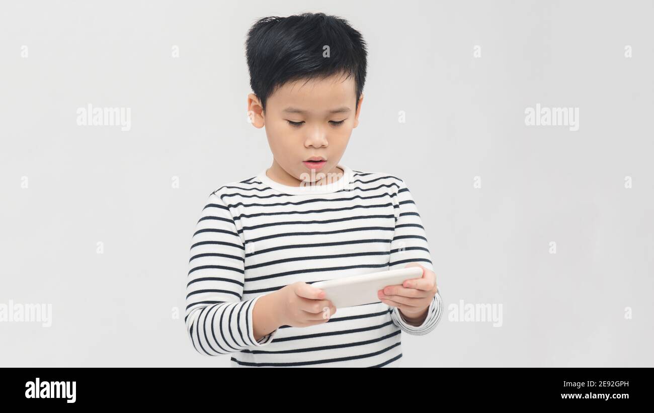 Portrait of an amused cute little kid playing games on smartphone ...
