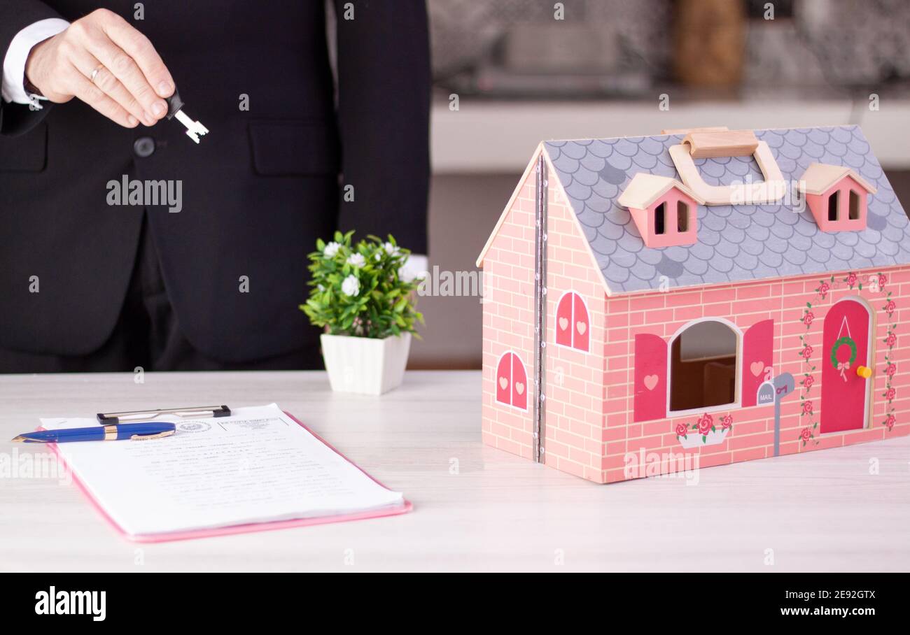 Image of an office table with a wooden house, a housing deed and an ...