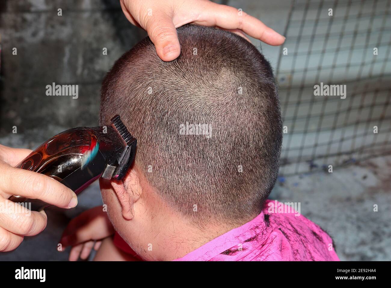 The barber is using a clipper to cut hair for the little boy Stock ...