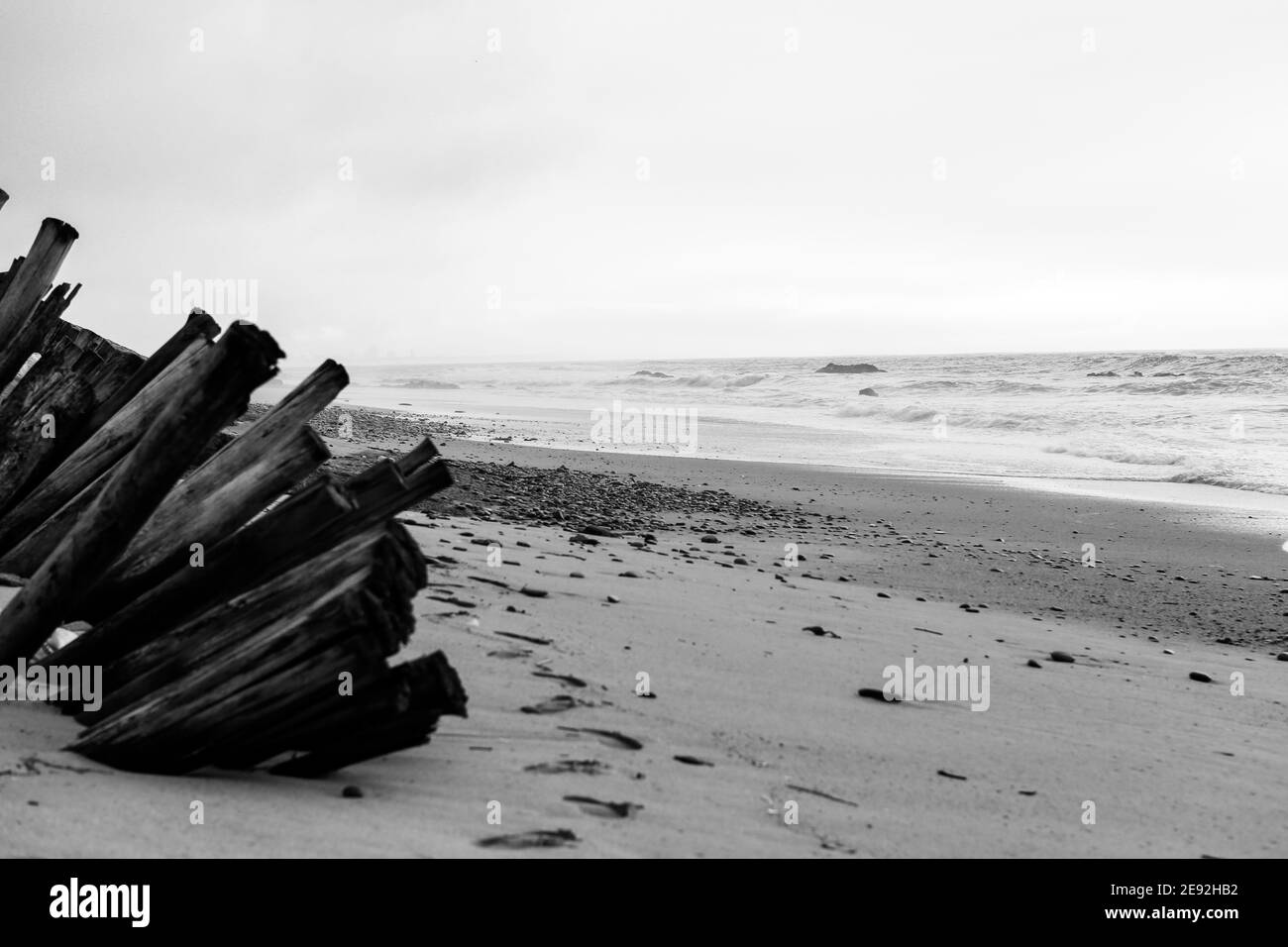 Grayscale shot of an empty beach and a wavy sea Stock Photo - Alamy