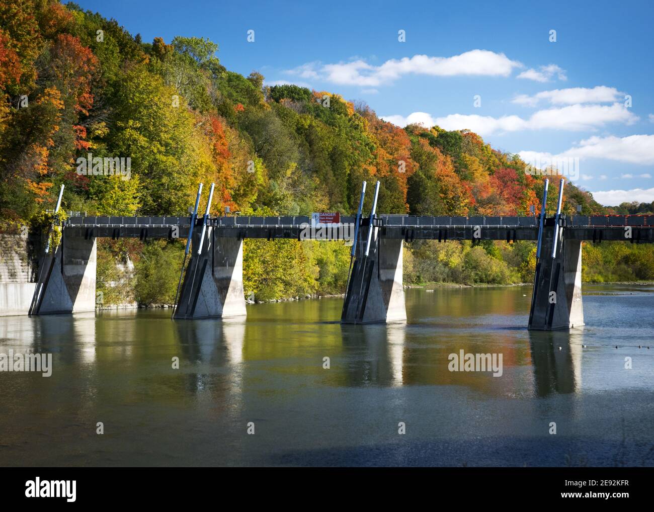 Stone bridge with a warning sign over the river and colorful autumn ...