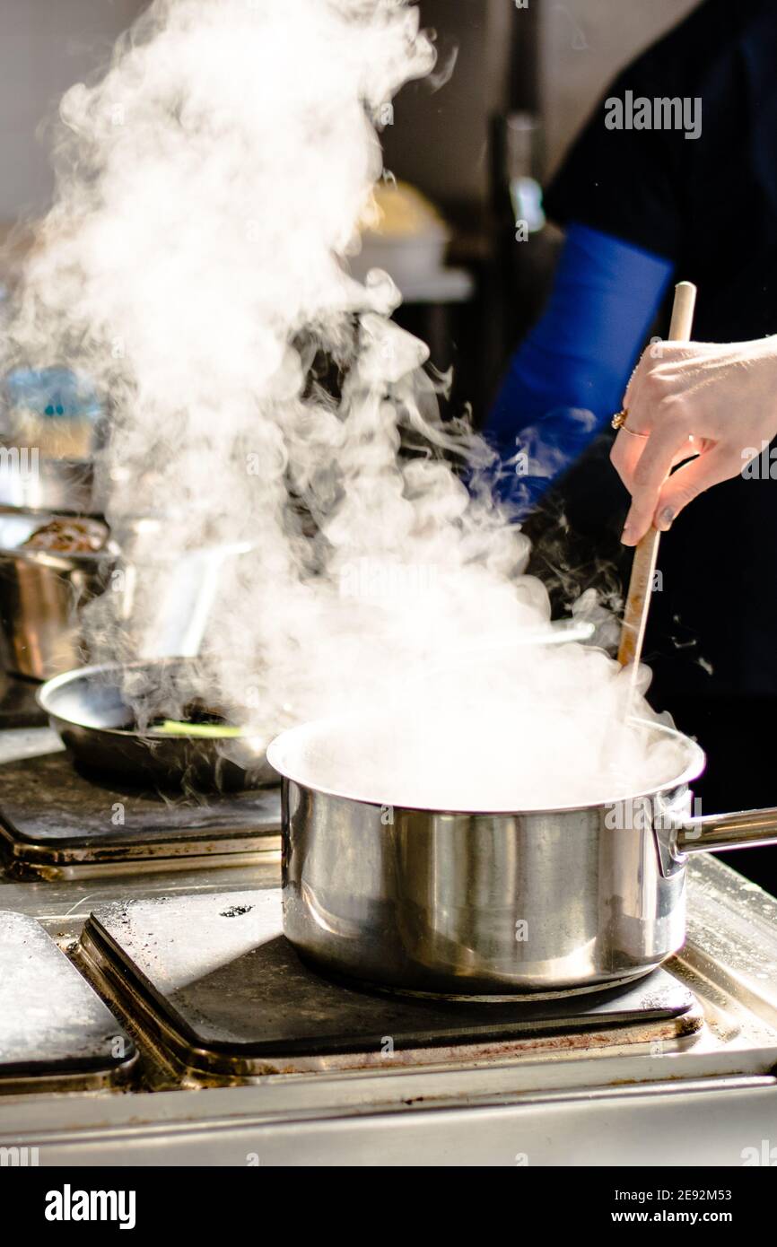 Chef cooking soup and water evaporating from a pot at a restaurant ...