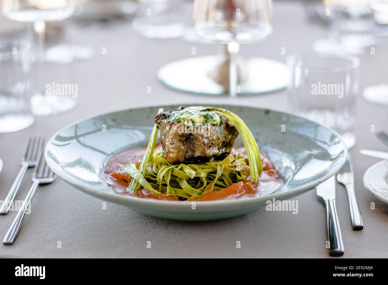 Grilled and flamed ox steak with green herb noodles in a tomato puree ...