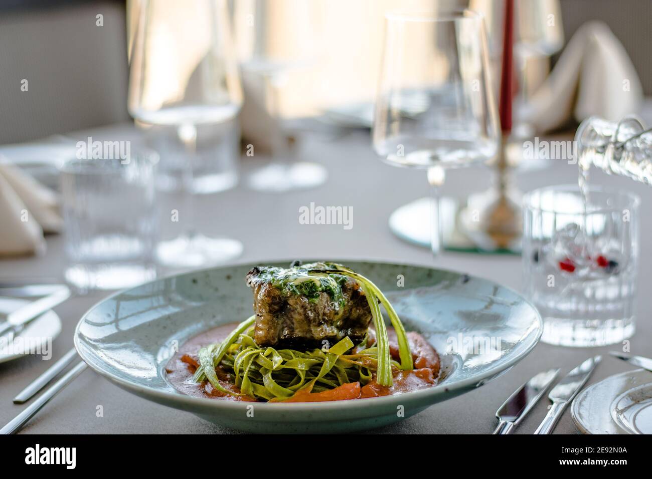 Grilled and flamed ox steak with green herb noodles in a tomato puree ...