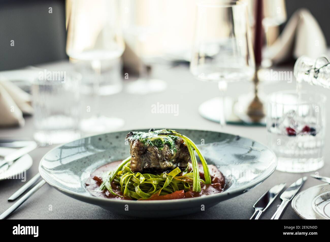 Grilled and flamed ox steak with green herb noodles in a tomato puree ...