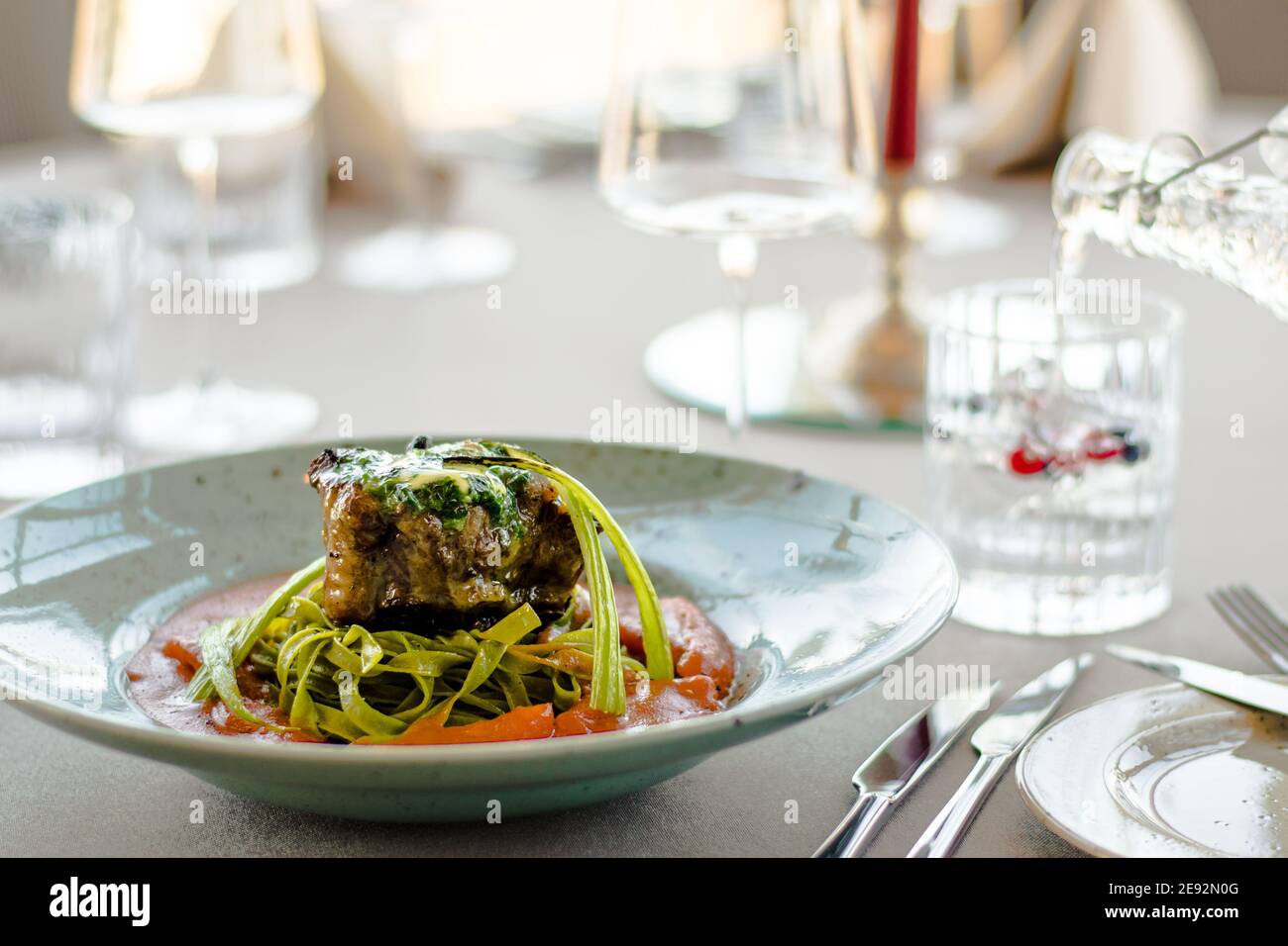 Grilled and flamed ox steak with green herb noodles in a tomato puree ...