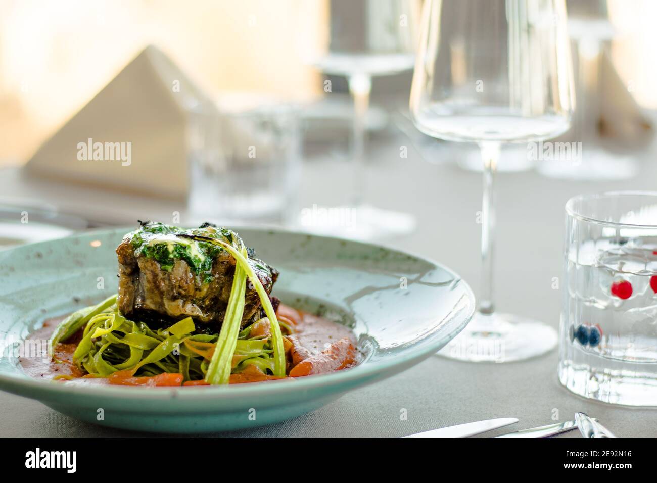 Grilled and flamed ox steak with green herb noodles in a tomato puree ...