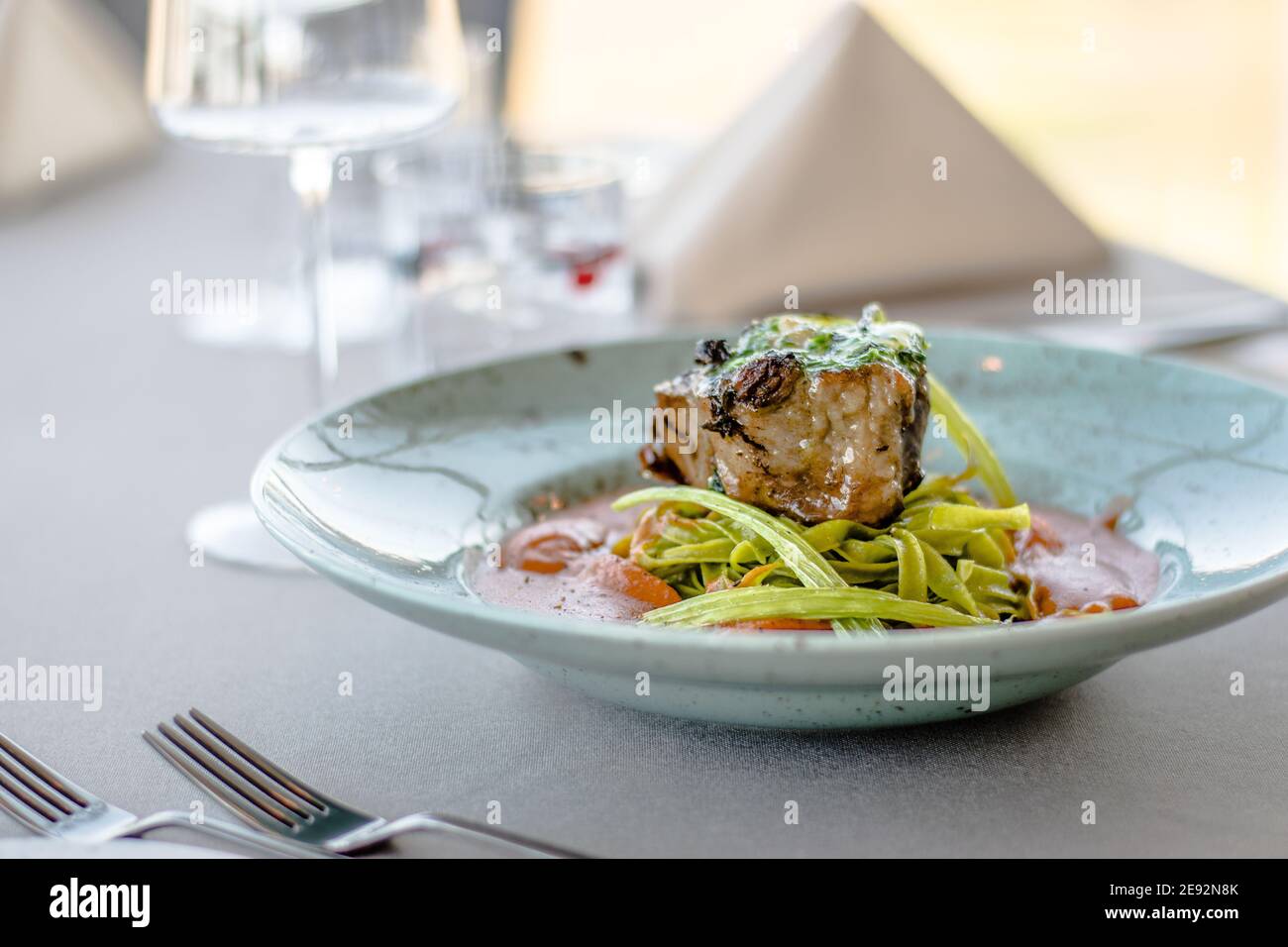Grilled and flamed ox steak with green herb noodles in a tomato puree ...