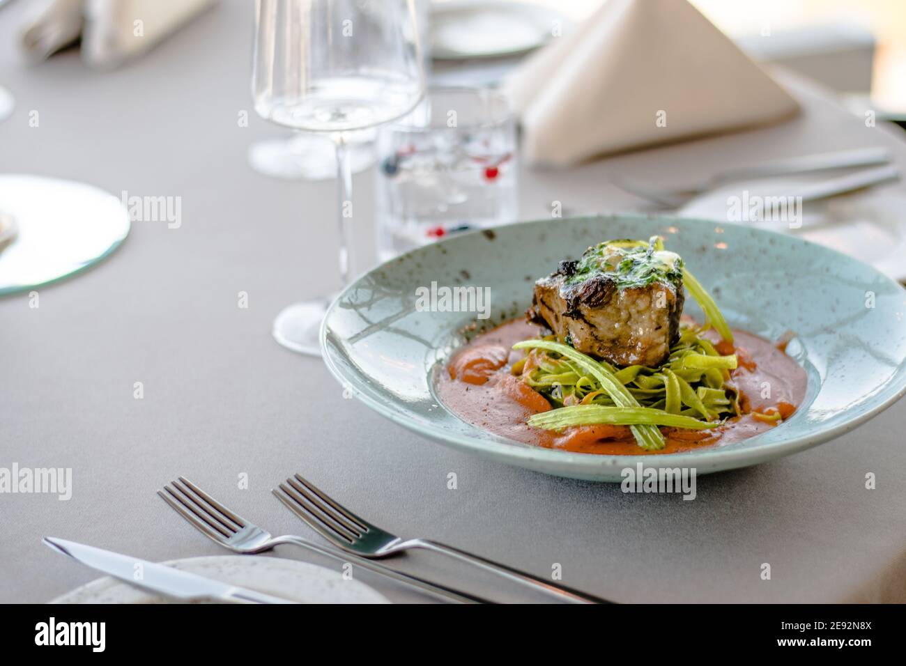 Grilled and flamed ox steak with green herb noodles in a tomato puree ...