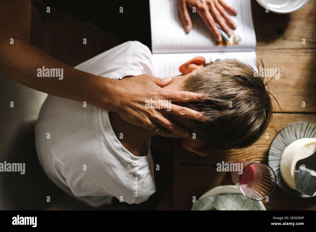 Mother's hand caressing tired son while studying at home Stock Photo ...