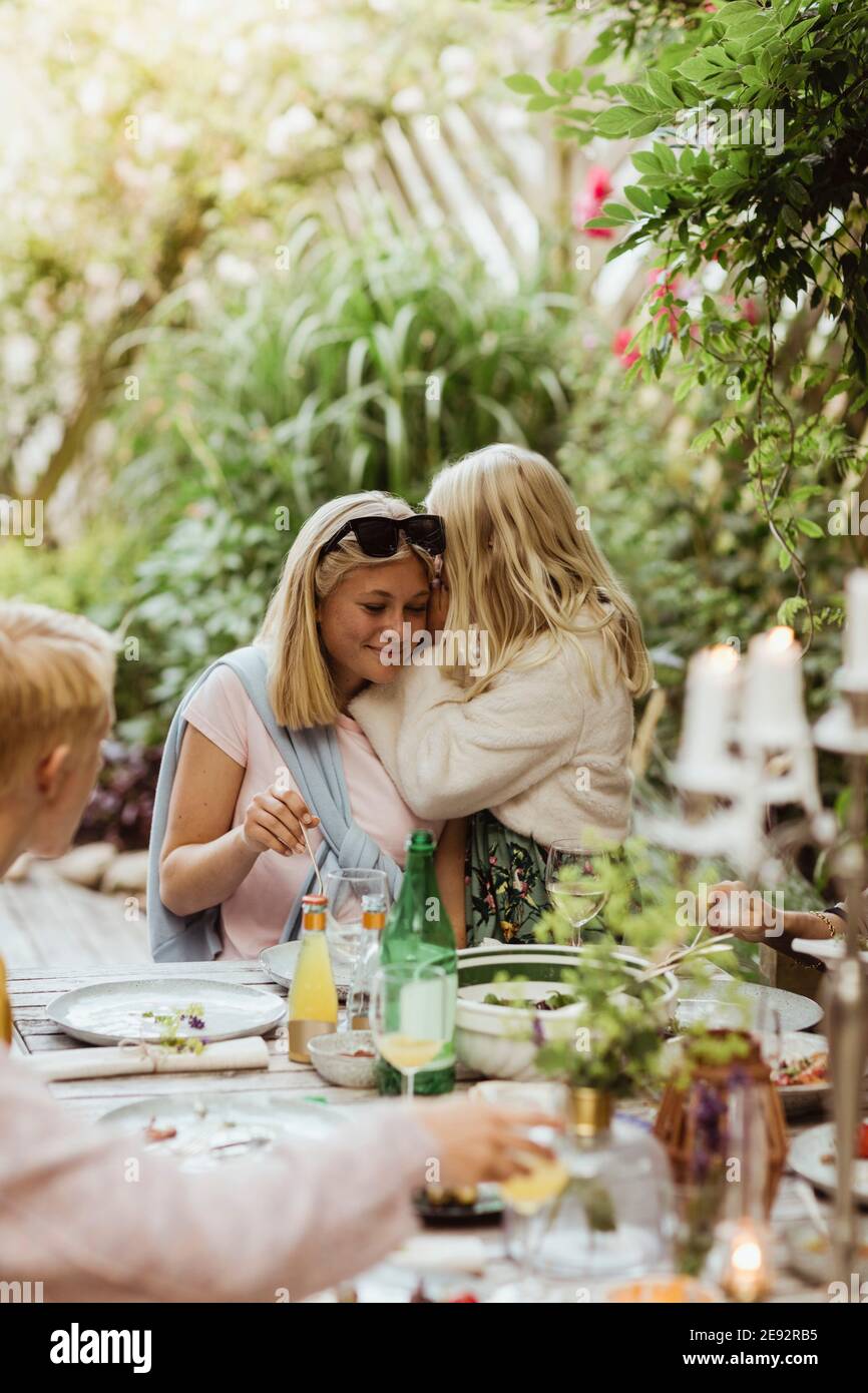 Girl whispering something in ear of female friend during party Stock ...