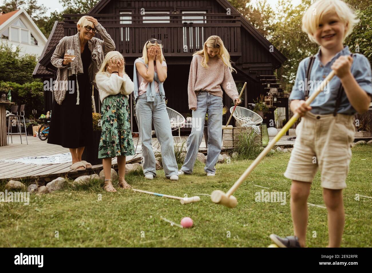Boy with polo mallet standing by family in back yard at evening Stock ...