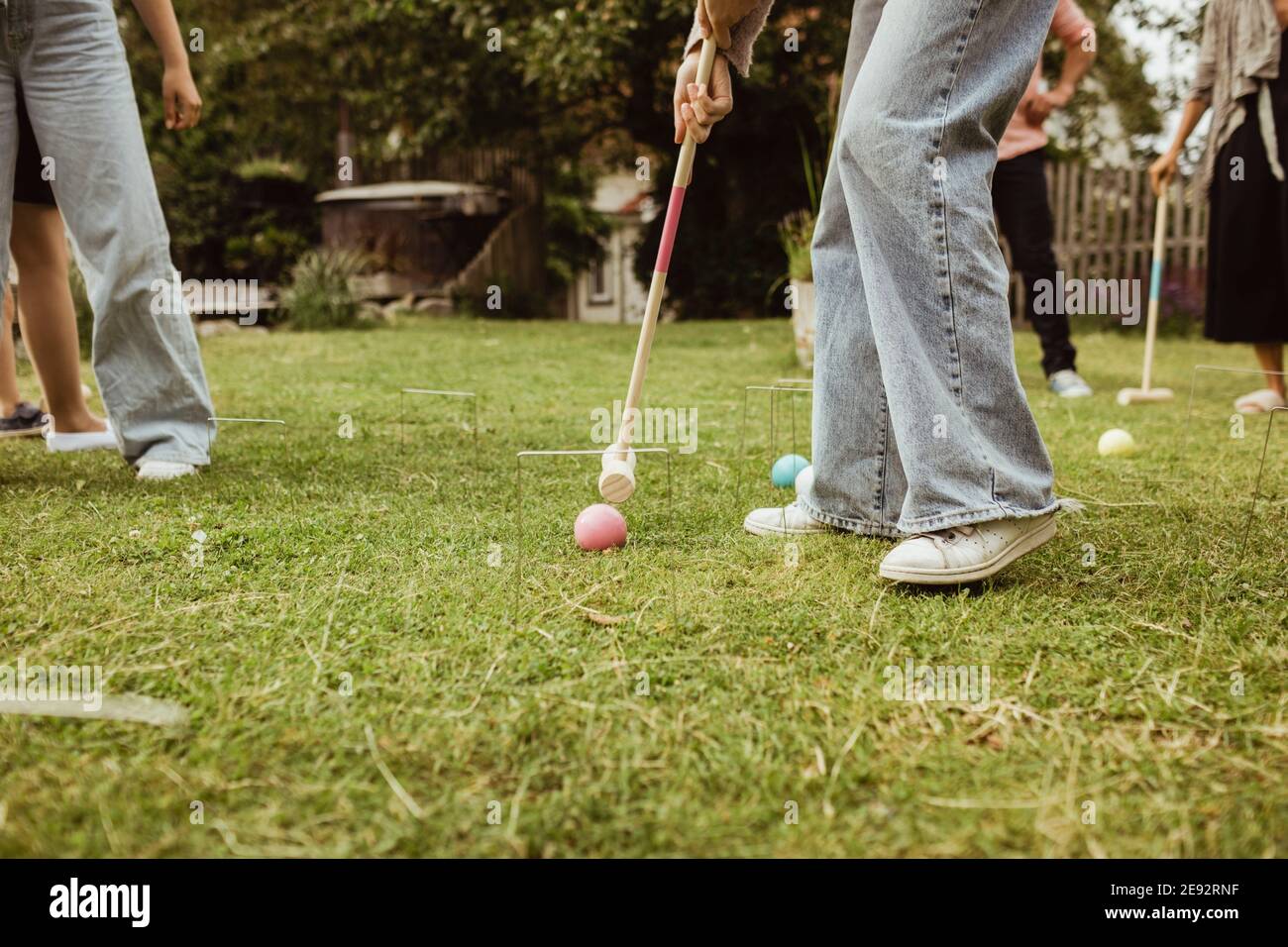 Low section of teenage girl playing polo with family in front yard ...