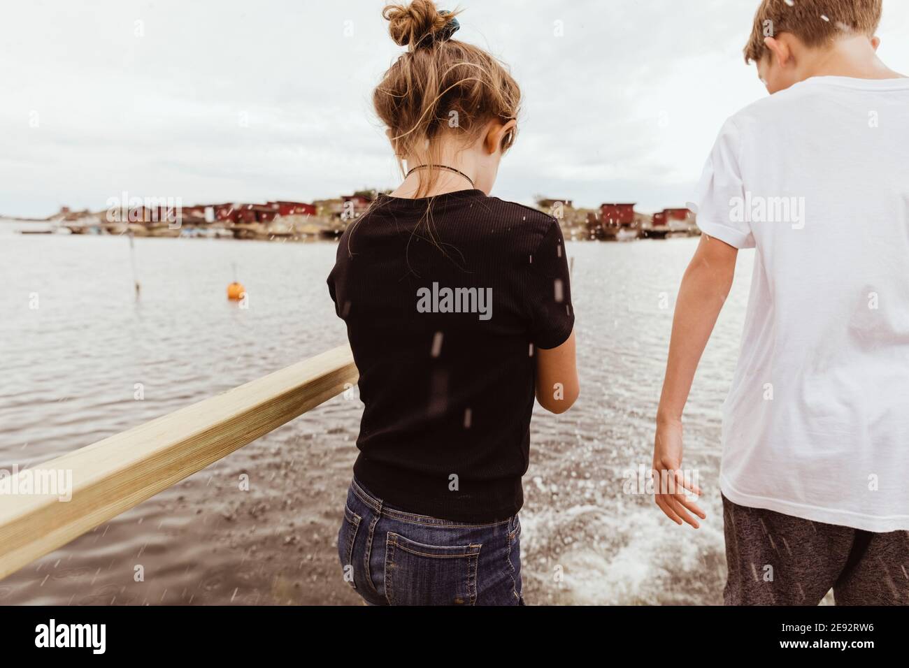 Rear view of siblings playing in water during vacation Stock Photo - Alamy