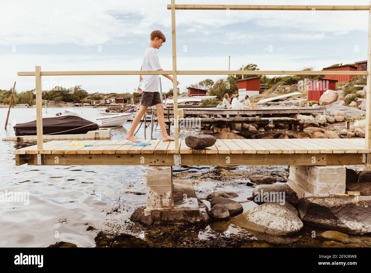 Pre-adolescent boy walking on jetty at marina Stock Photo - Alamy